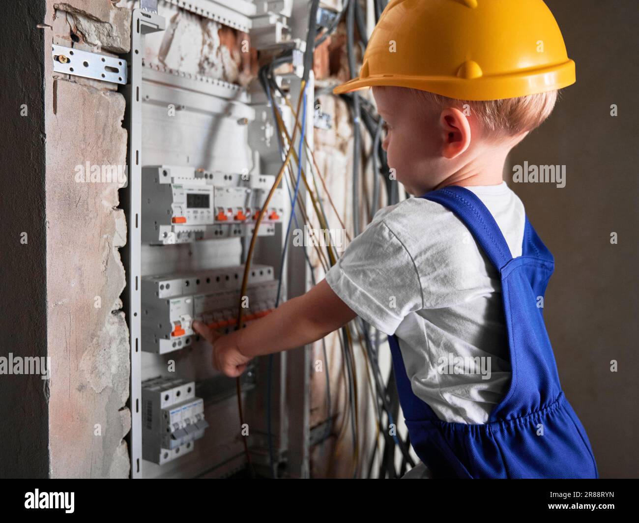 Side view of child fixing electrical switchboard or distribution board ...
