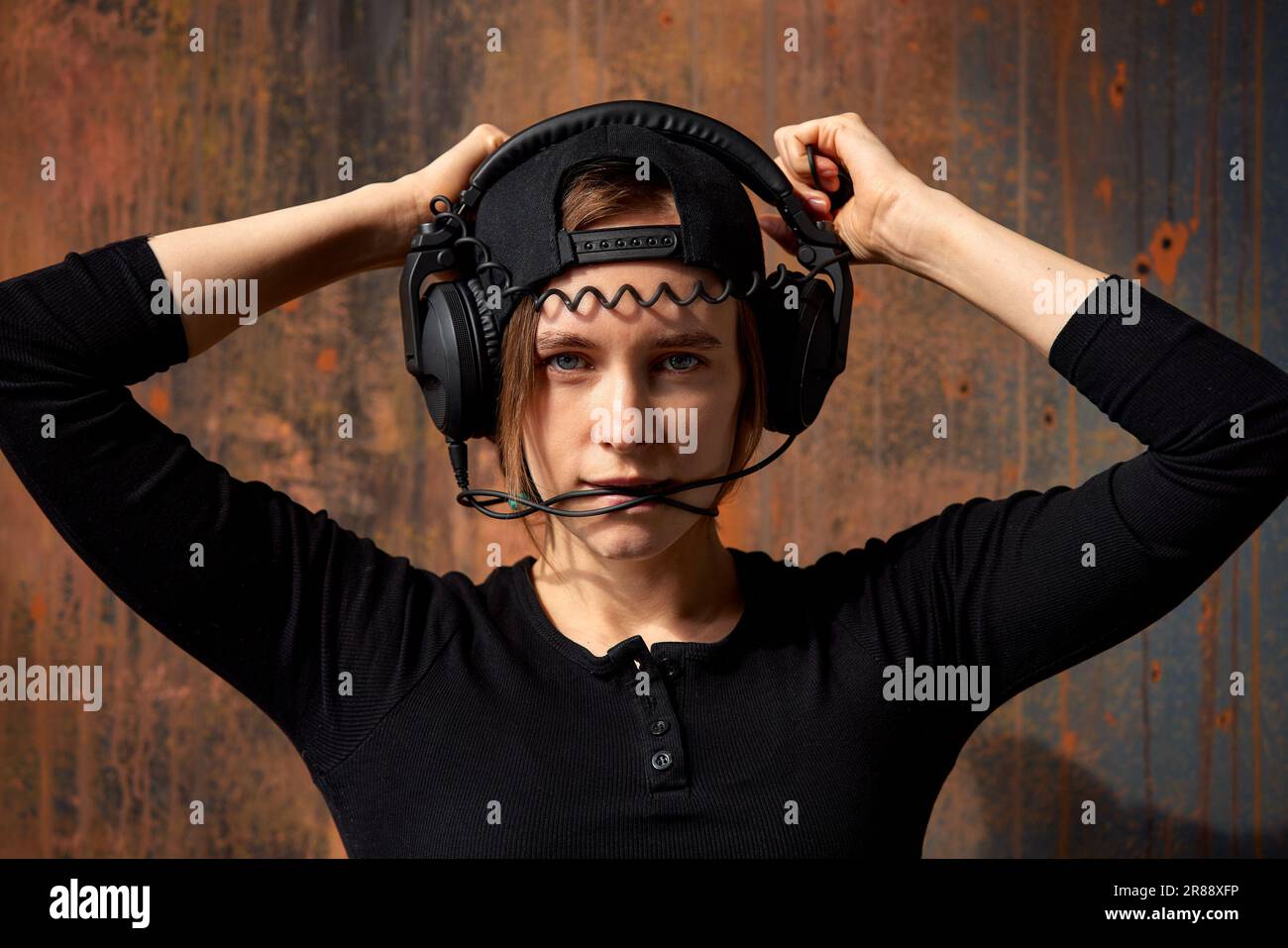 A young long-haired DJ girl in a black top, black baseball cap and ...