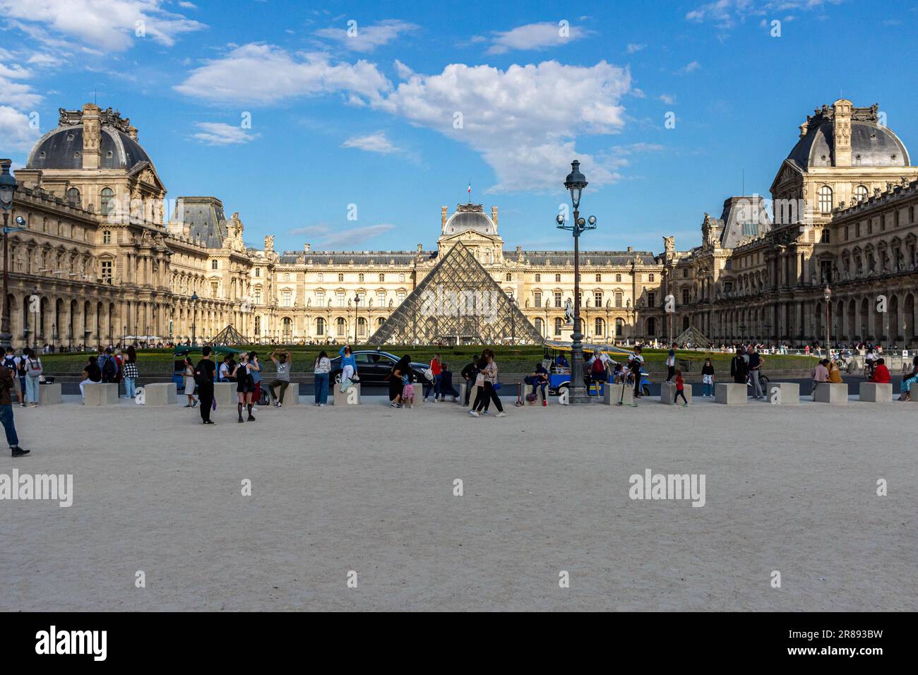 A diverse group of people is seen strolling in front of a grandiose ...