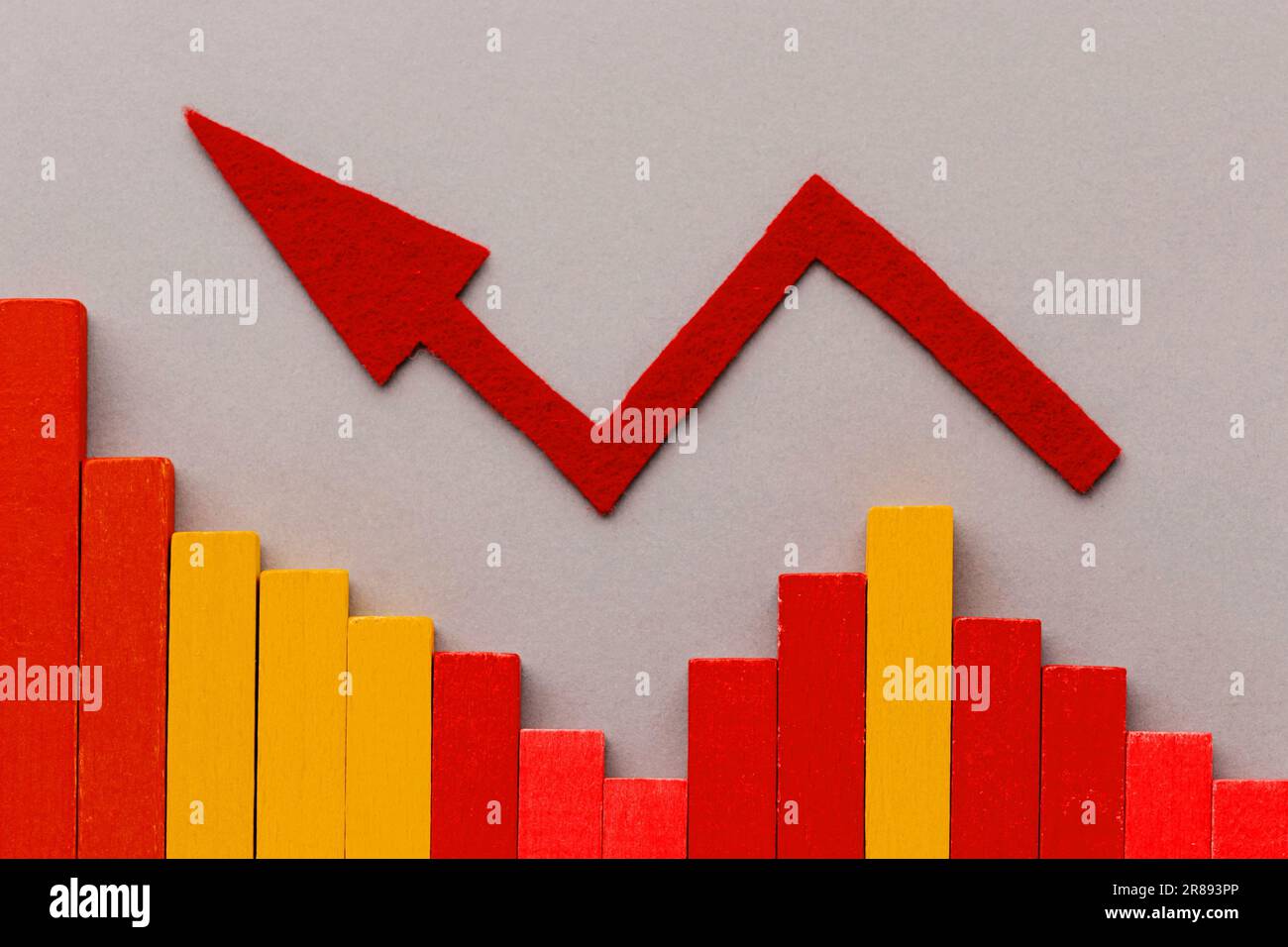 A paper cut-out of a red arrow pointing upwards, over a graph Stock ...