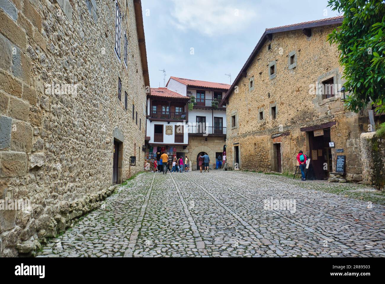An ancient cobblestone street lined with vibrant buildings is bustling ...