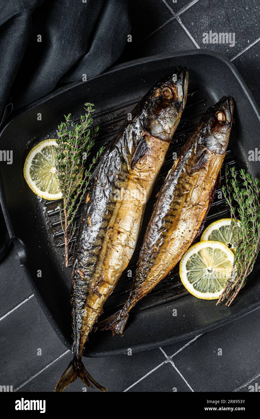 Grilled mackerel fish with lemon, herbs and spices in a skillet. Black ...