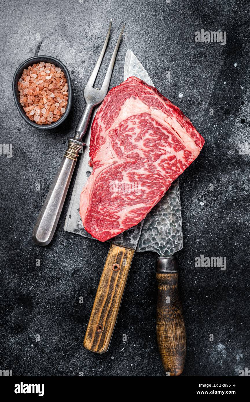 Butcher table with wagyu Rib Eye steak, raw beef meat. Black background ...