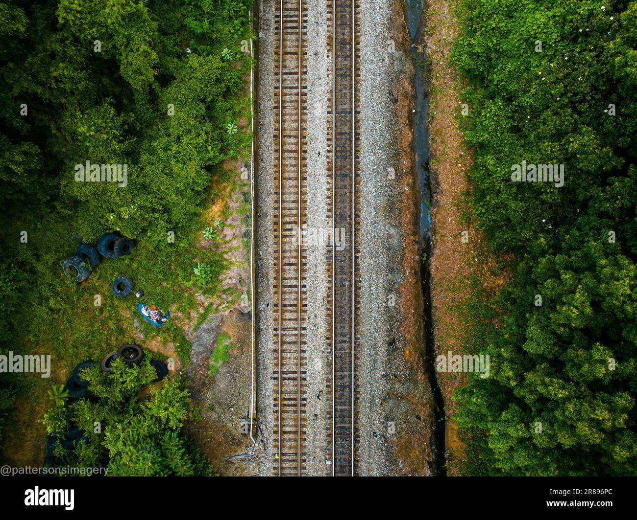 An aerial view of the railroad tracks through a forest surrounded by ...