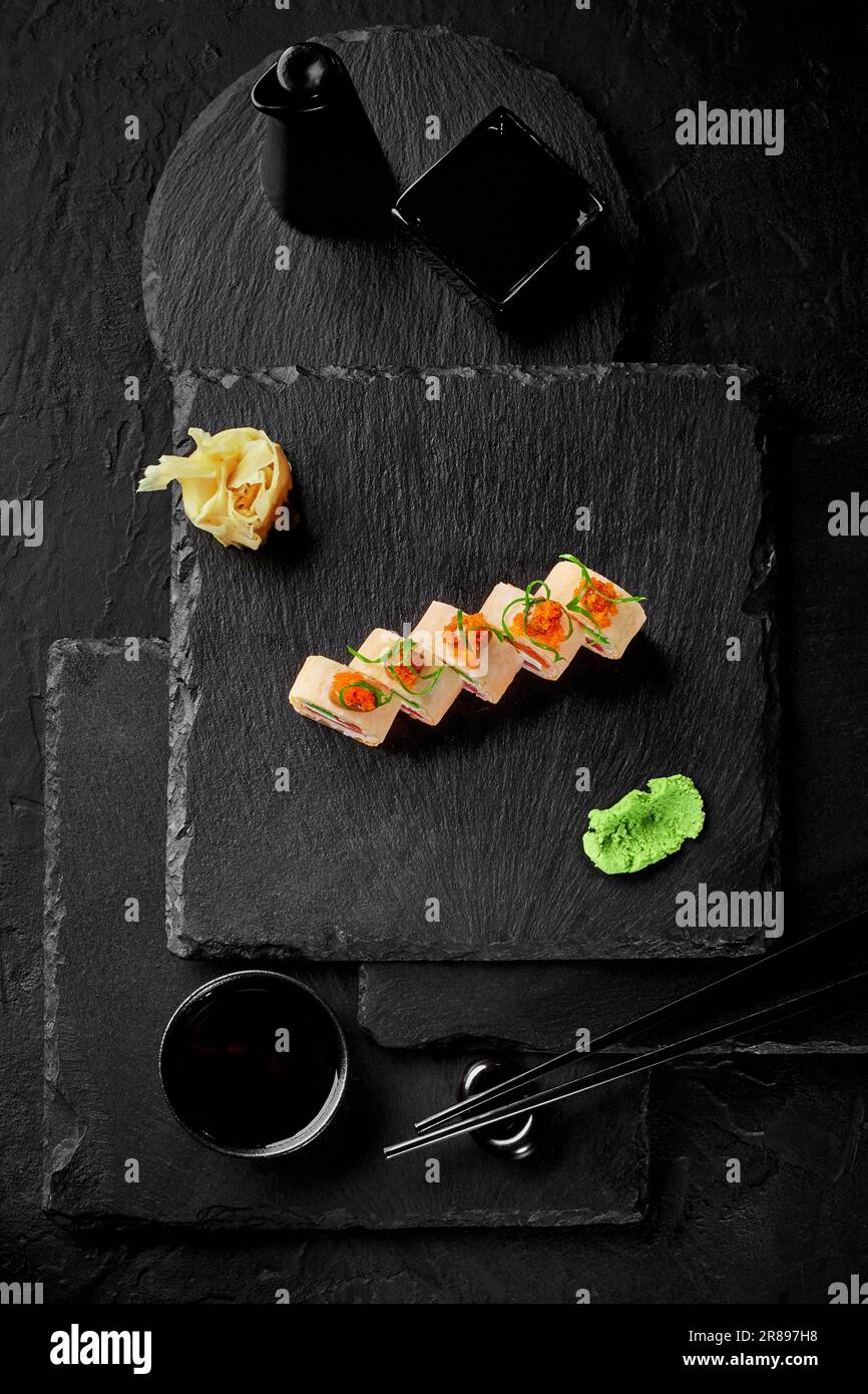 Sushi rolls in mamenori topped with tobiko served with wasabi, gari and ...