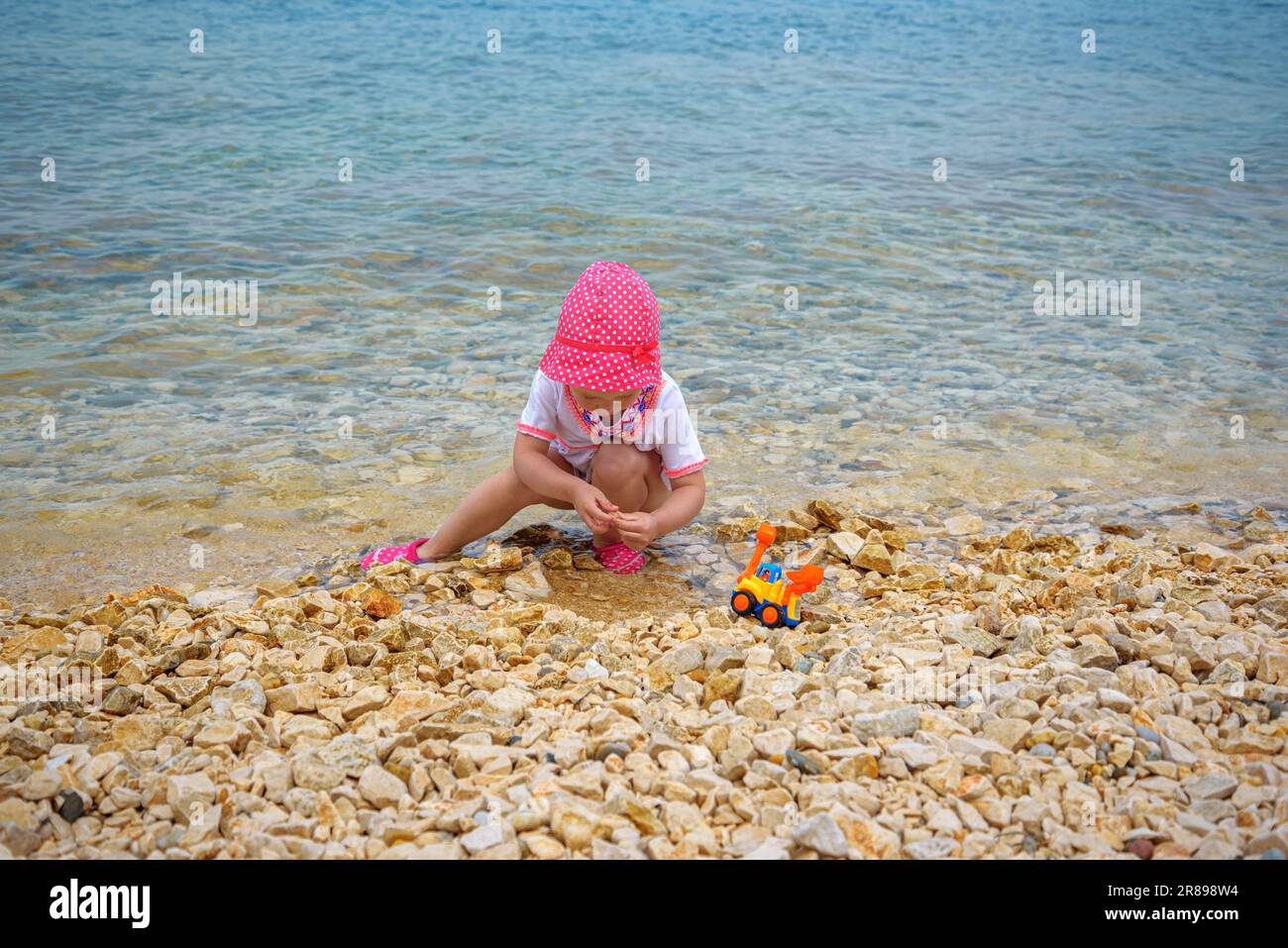 Child playing with pebbles on the beach Stock Photo - Alamy