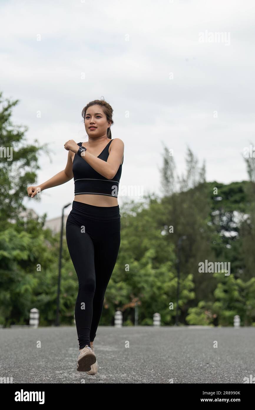 Happy woman wearing sportswear jogging in the park. Young beautiful ...