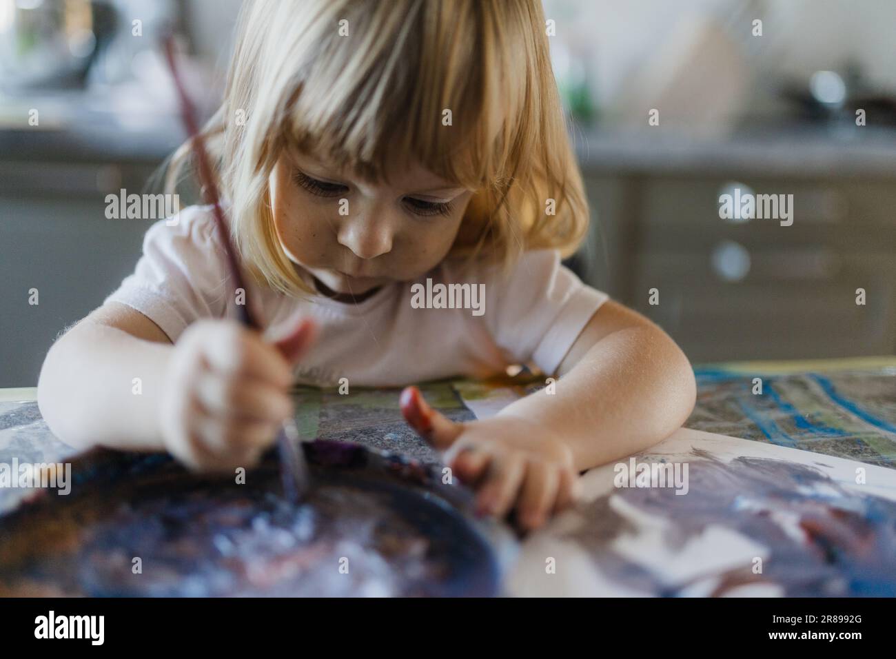 Cute little girl painting with tempera paint using a paintbrush Stock ...