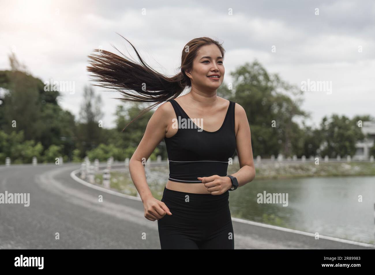 Happy woman wearing sportswear jogging in the park. Young beautiful ...
