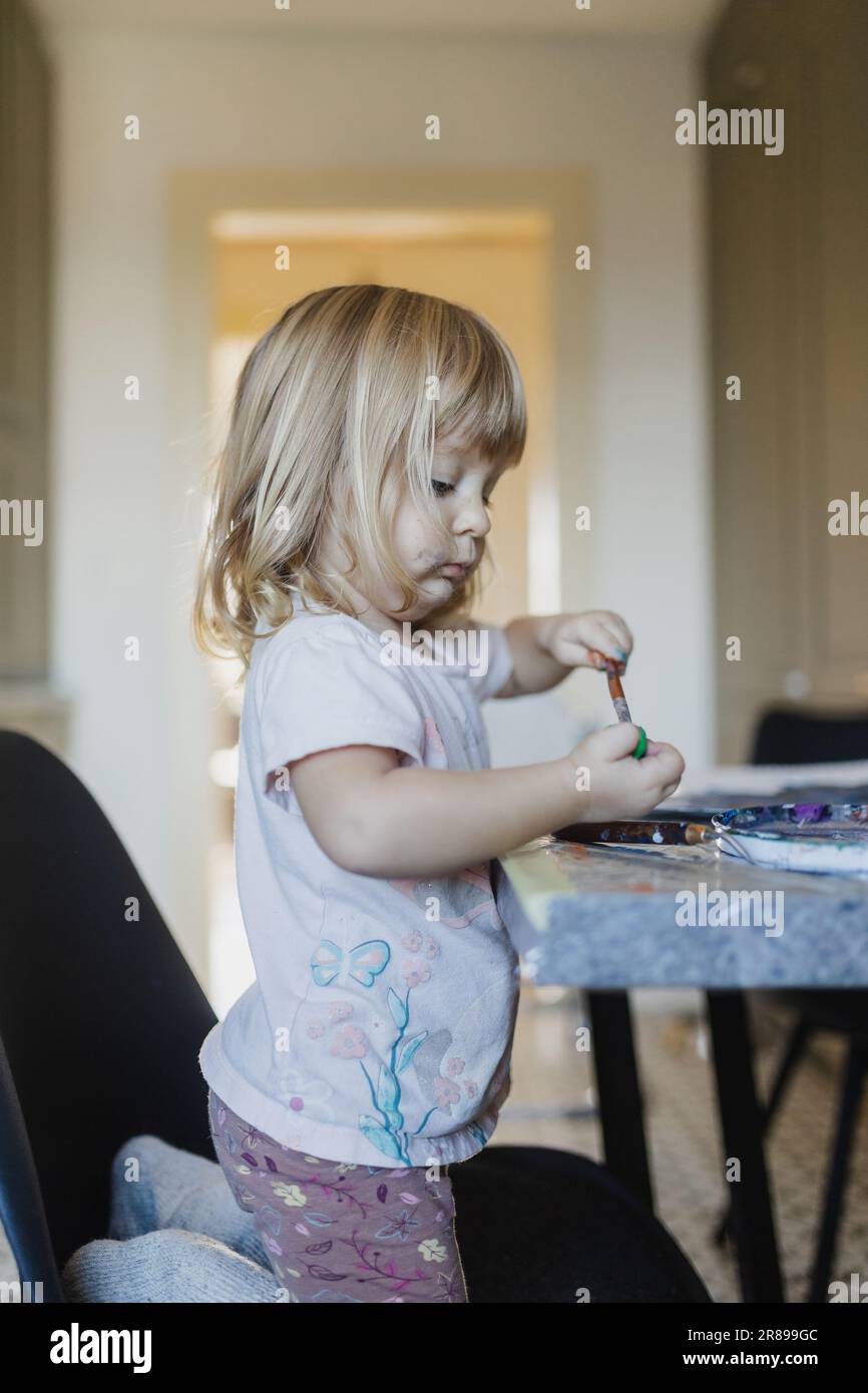 Cute little girl painting with tempera paint using a paintbrush Stock ...