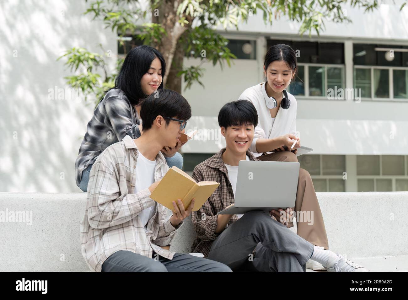 University students sitting together at table with books and laptop and ...