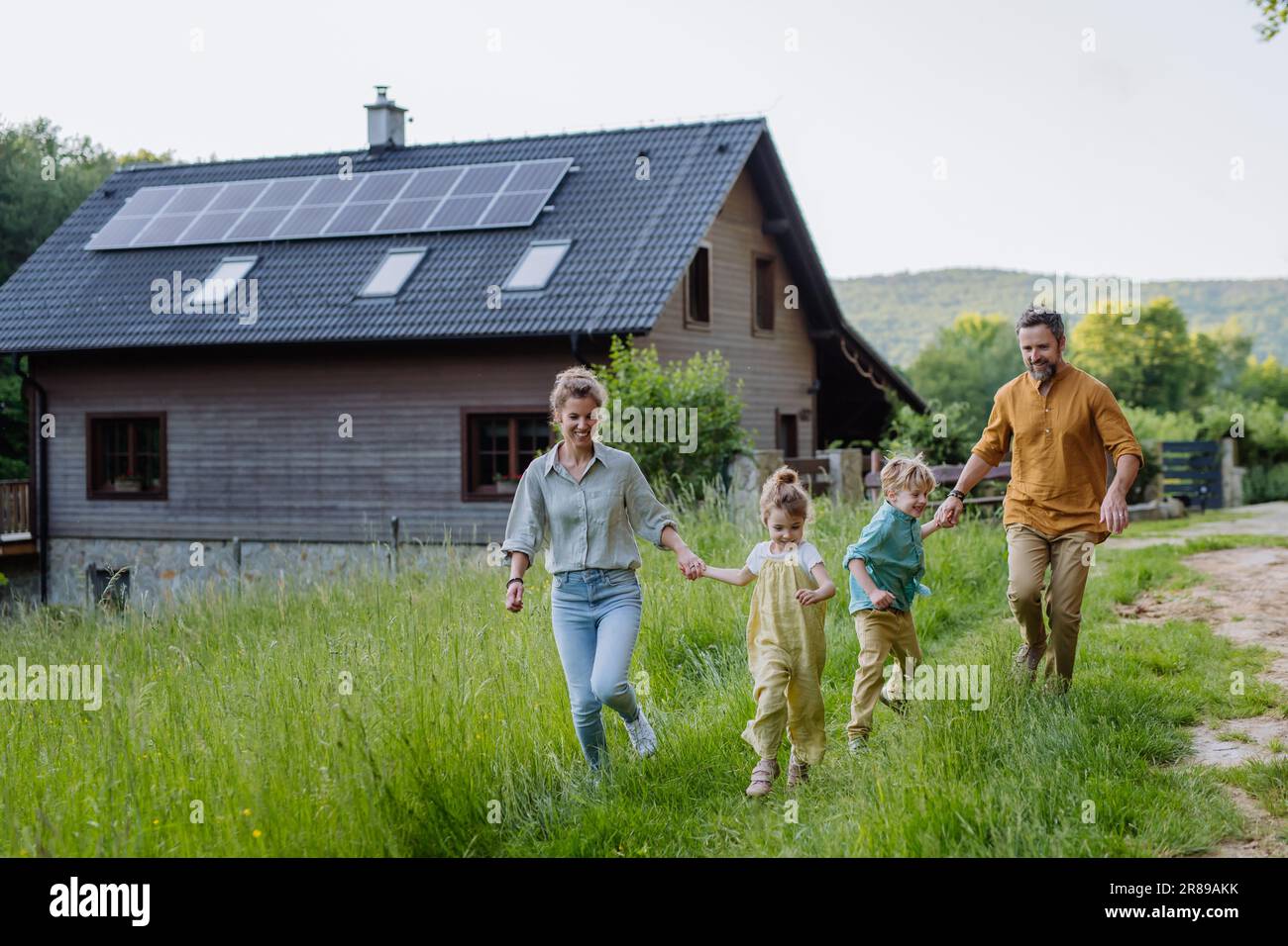 Happy family in front of their house with solar panels on the roof ...