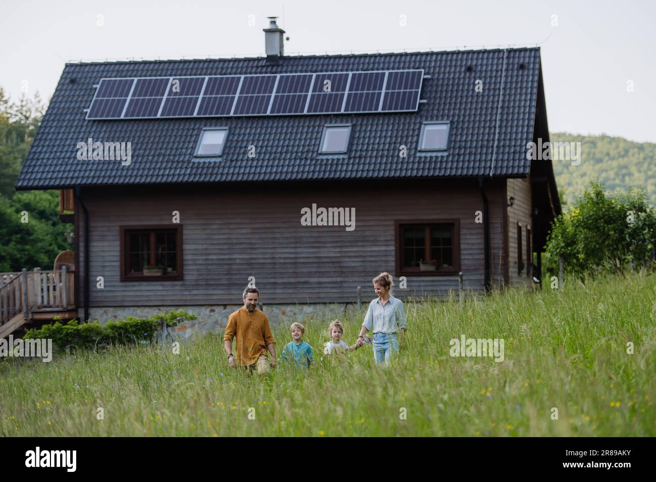 Happy family in front of their house with solar panels on the roof ...