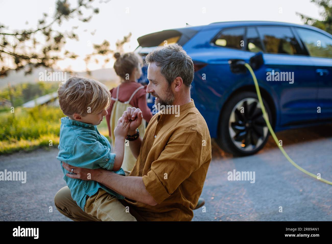 Father with his kids waiting for electric car charging Stock Photo - Alamy