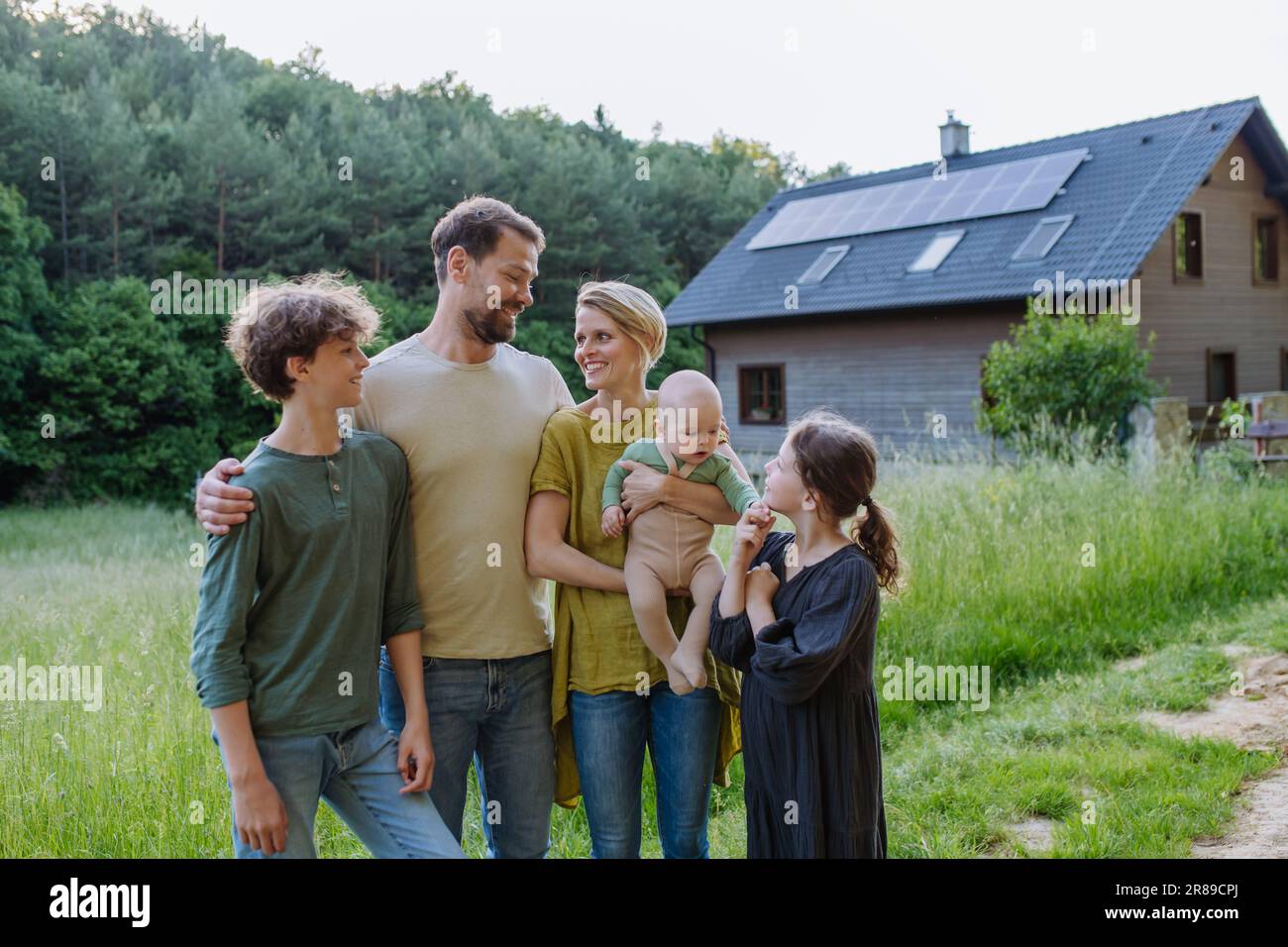 Happy family near their house with solar panels. Alternative energy ...