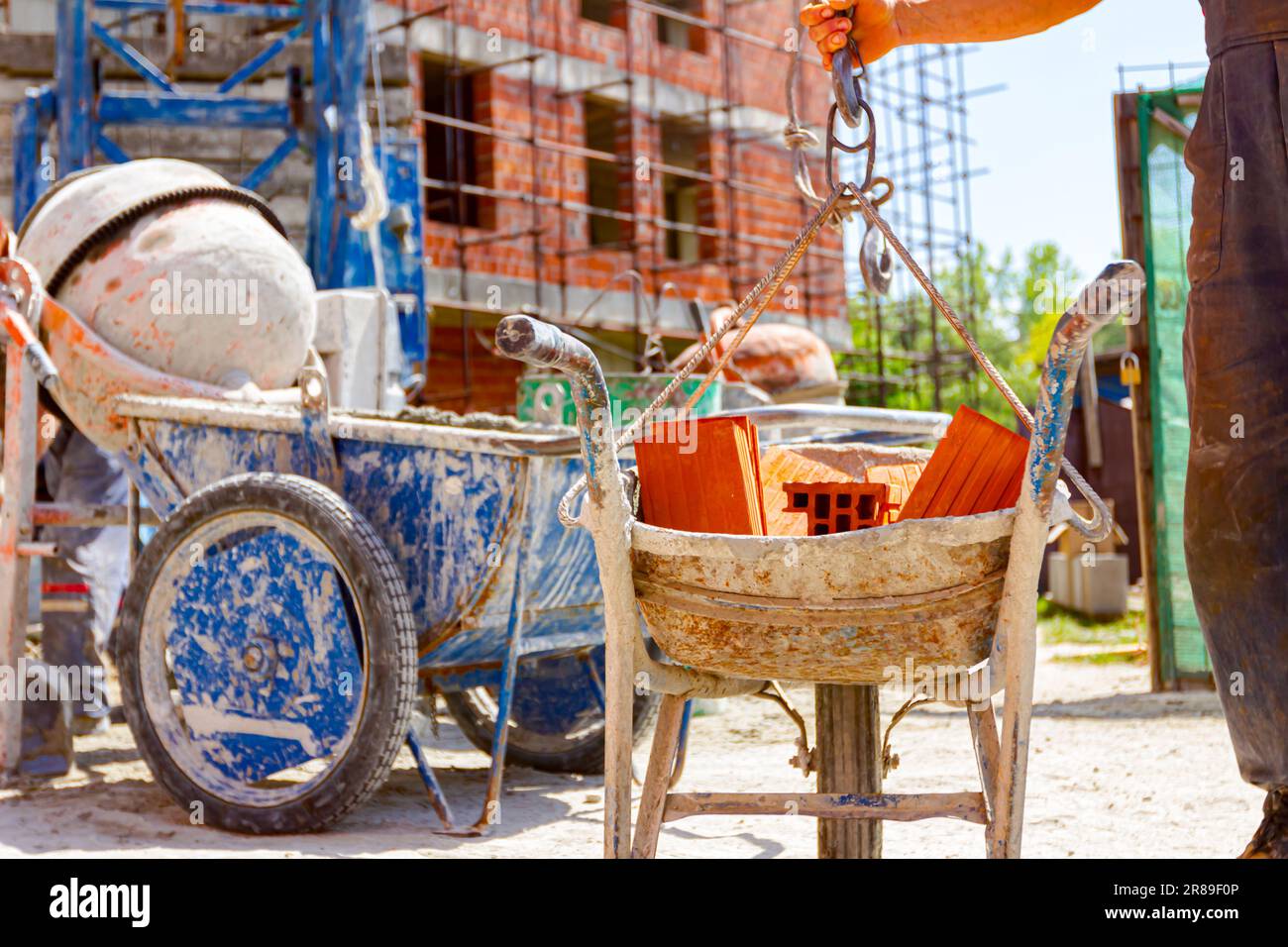 Construction worker is attaching crane hooks to industrial tipping ...