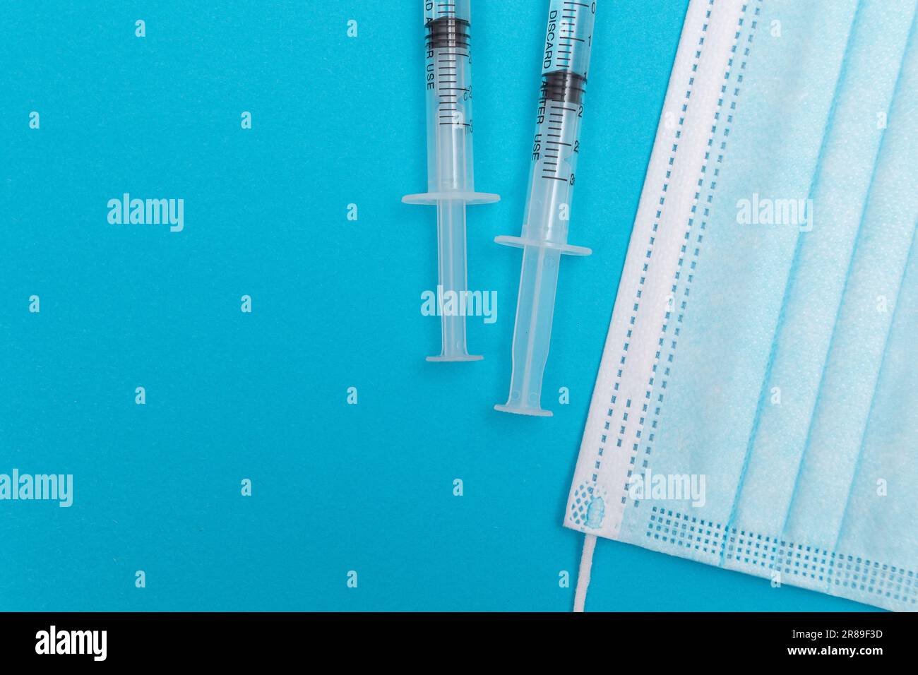 Several Syringe and Face Mask on Blue Table - Top View. Syringes are ...