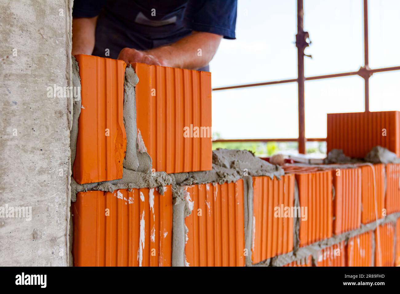 Mason, bricklayer worker is using red blocks to mount a wall at ...
