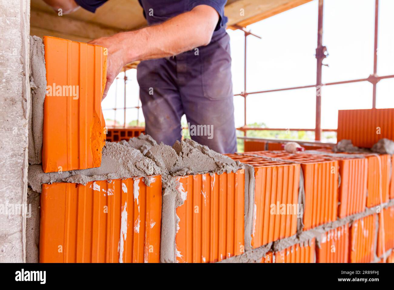 Mason, bricklayer worker is using red blocks to mount a wall at ...