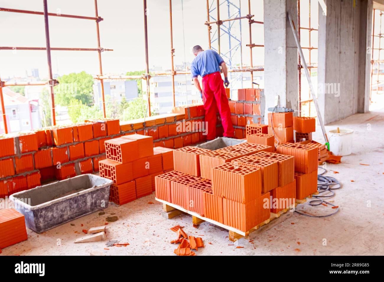Wooden pallet with a pile of red blocks, mason bricklayer worker is ...