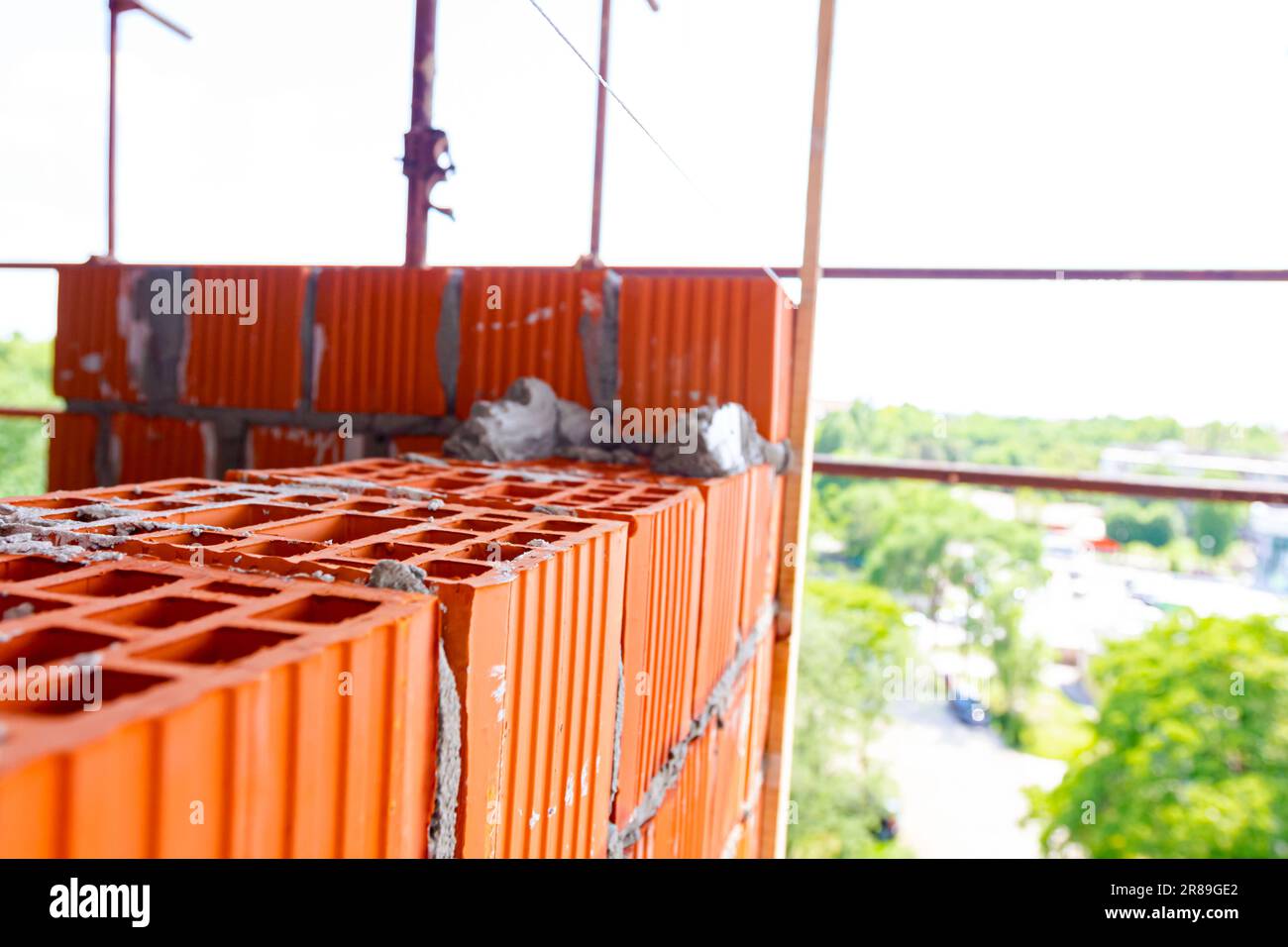 Mason, bricklayer worker is using red blocks to mount a wall next the ...