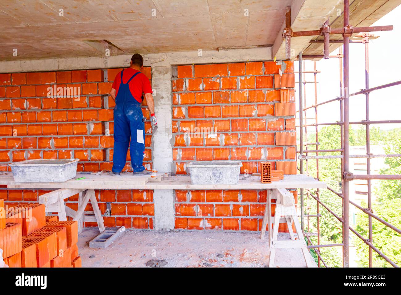Mason, worker is standing on wooden scaffolding, a platform made of ...