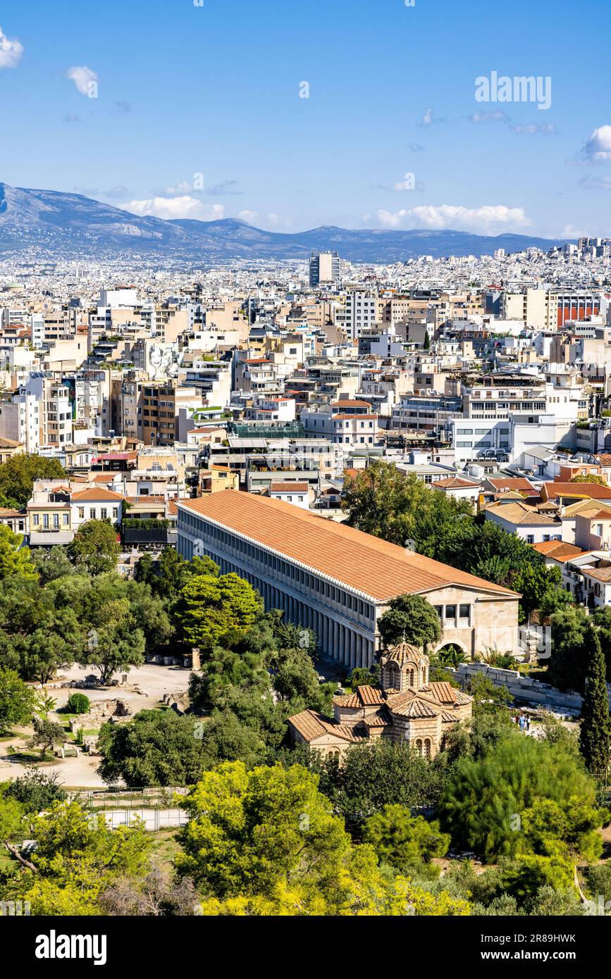 A cityscape of Athens surrounded by greenery under a blue sky and ...