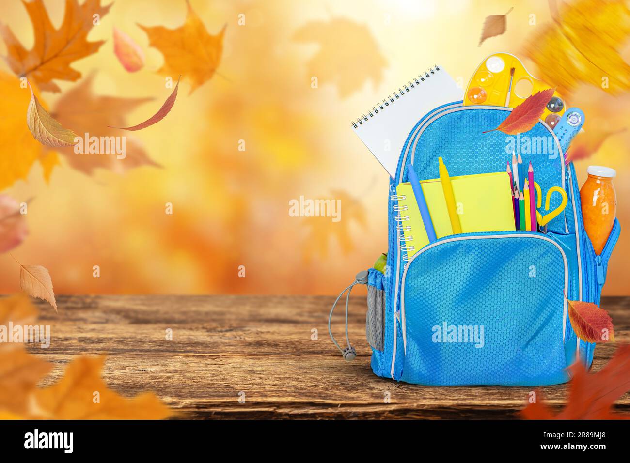Blue backpack with school supplies on autumn background. Copy space ...