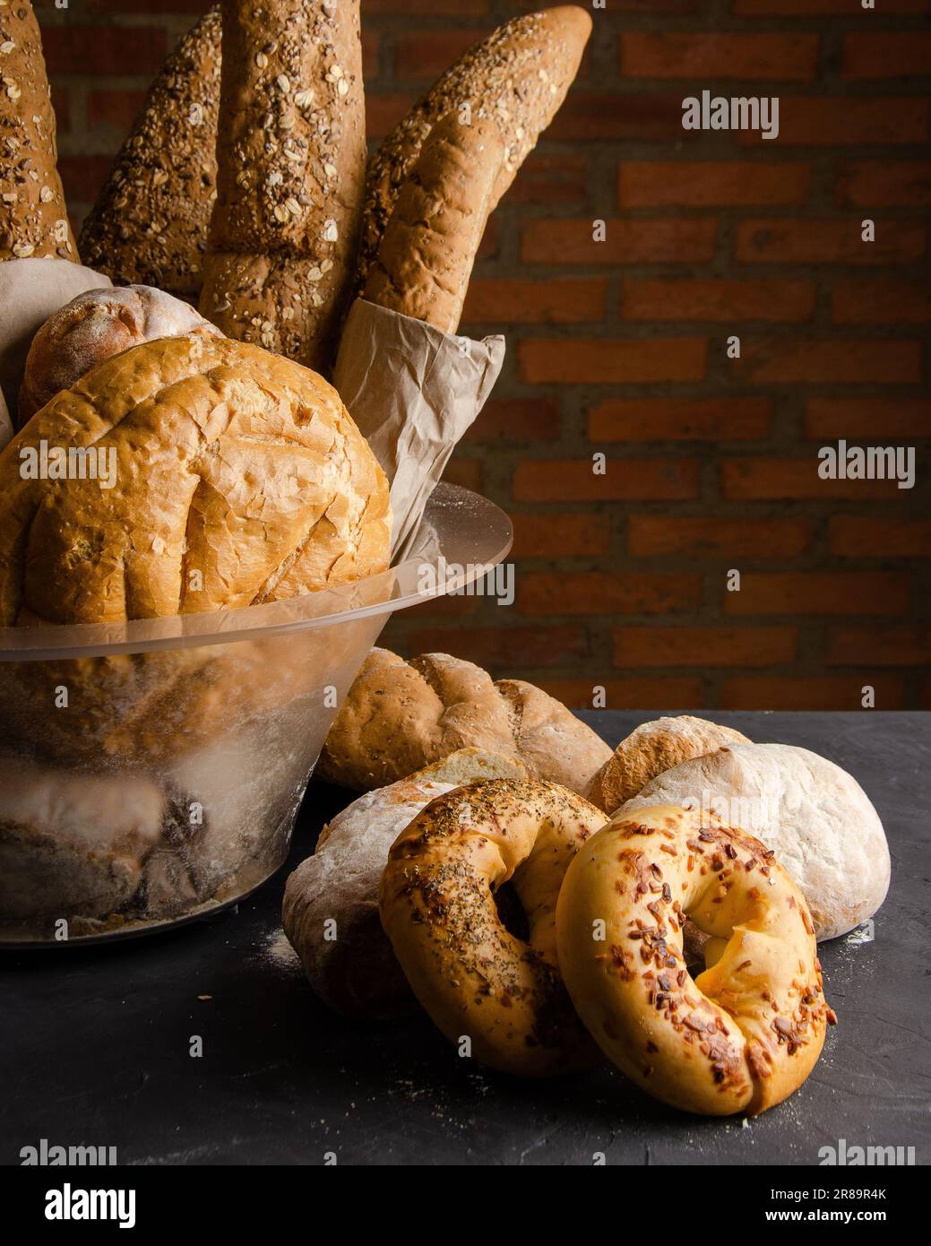 Basket with different types of breads. On black background, brick wall ...