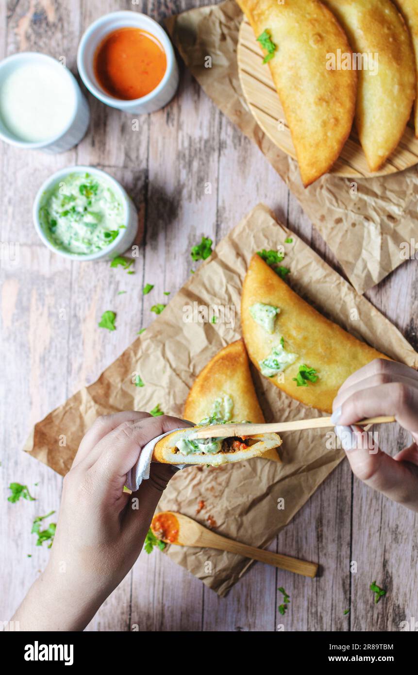 Girl's hands with empanada typical food from Venezuela adding gasacaca ...