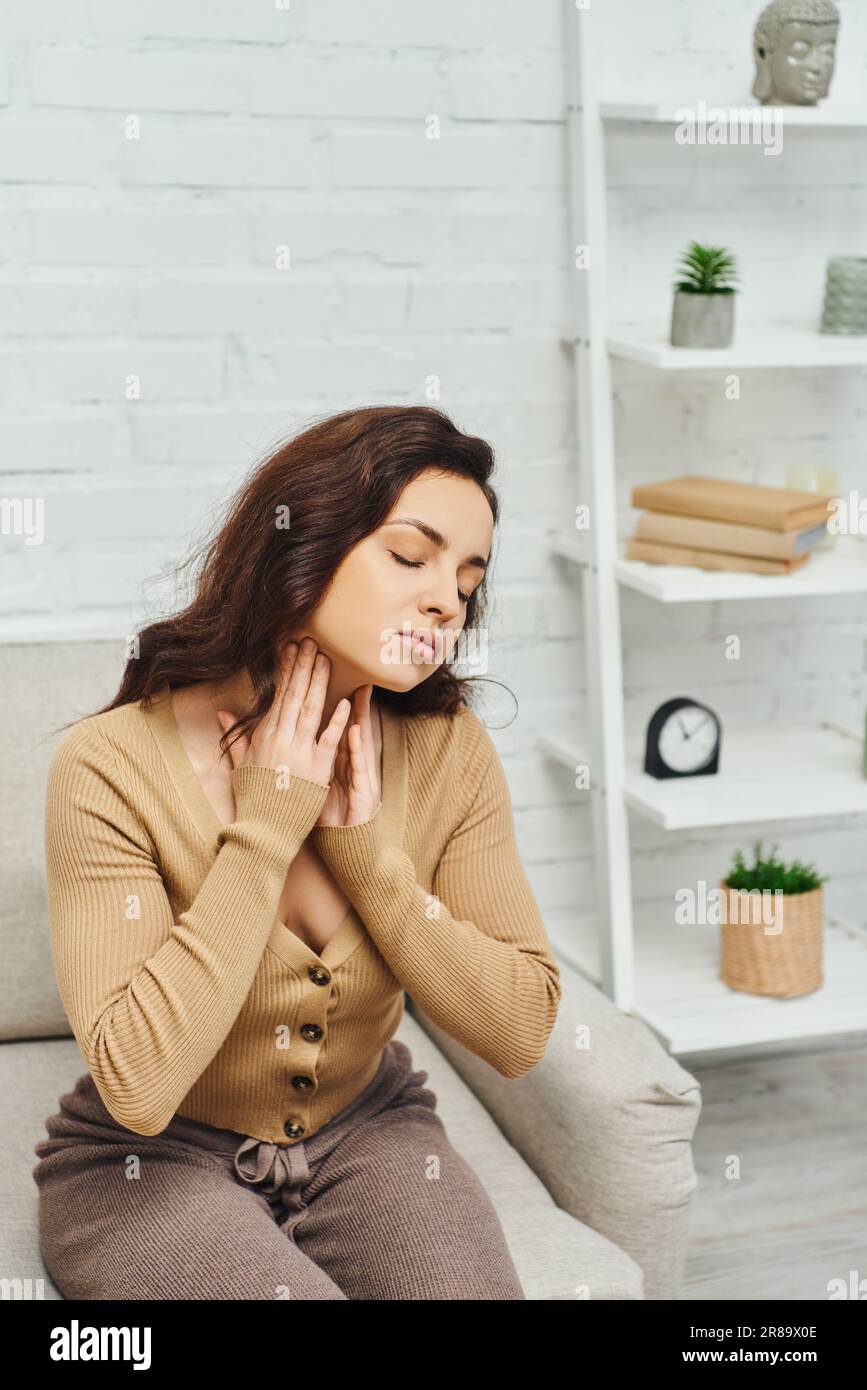 Brunette woman in casual clothes massaging lymphatic nodes on neck ...