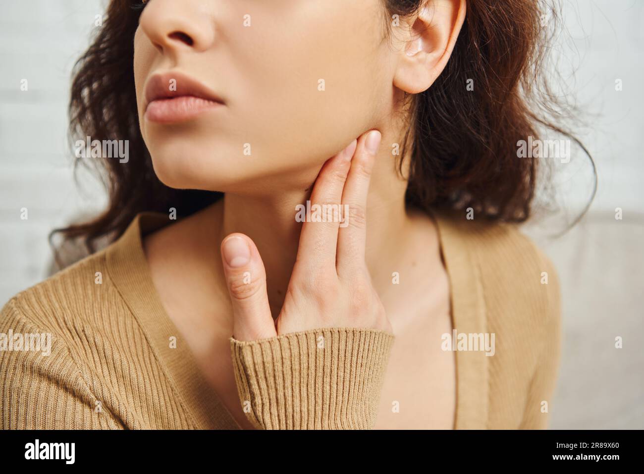 Cropped view of young brunette woman in brown jumper massaging ...