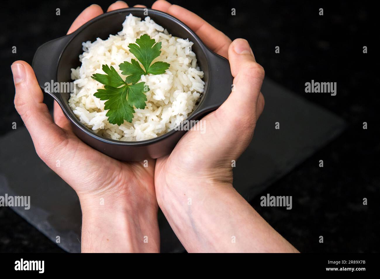 Dry white rice, as an accompaniment to various dishes. Hands holding ...