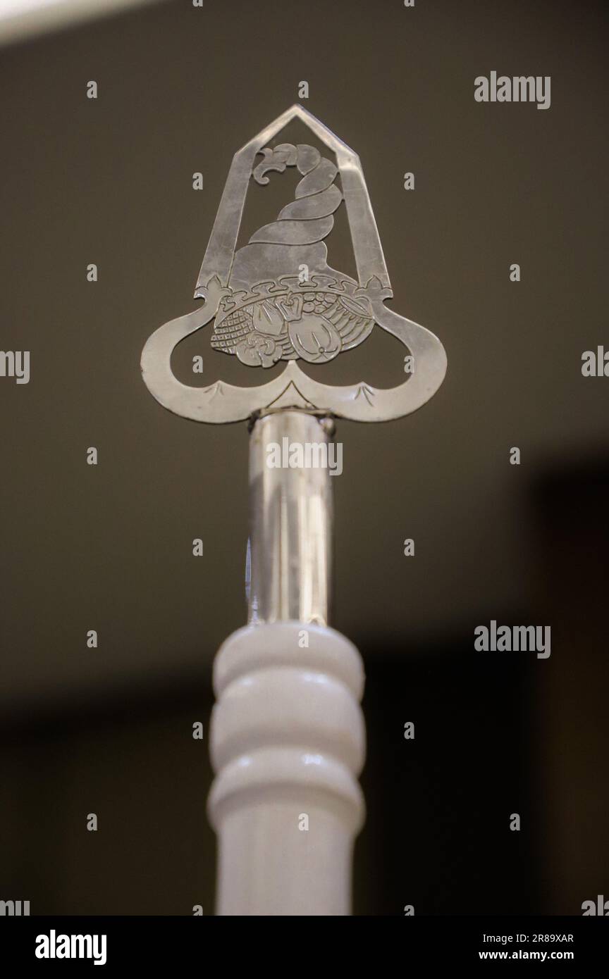 A white metal pole is illuminated in the dark of night, featuring a ...