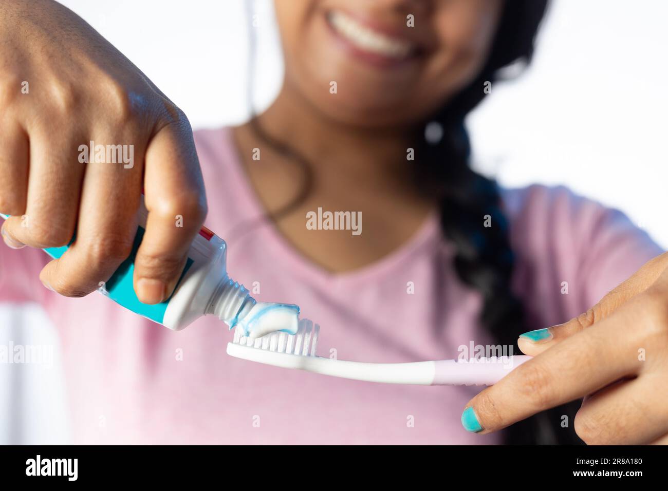 An Indian woman female girl applying toothpaste on toothbrush on white ...