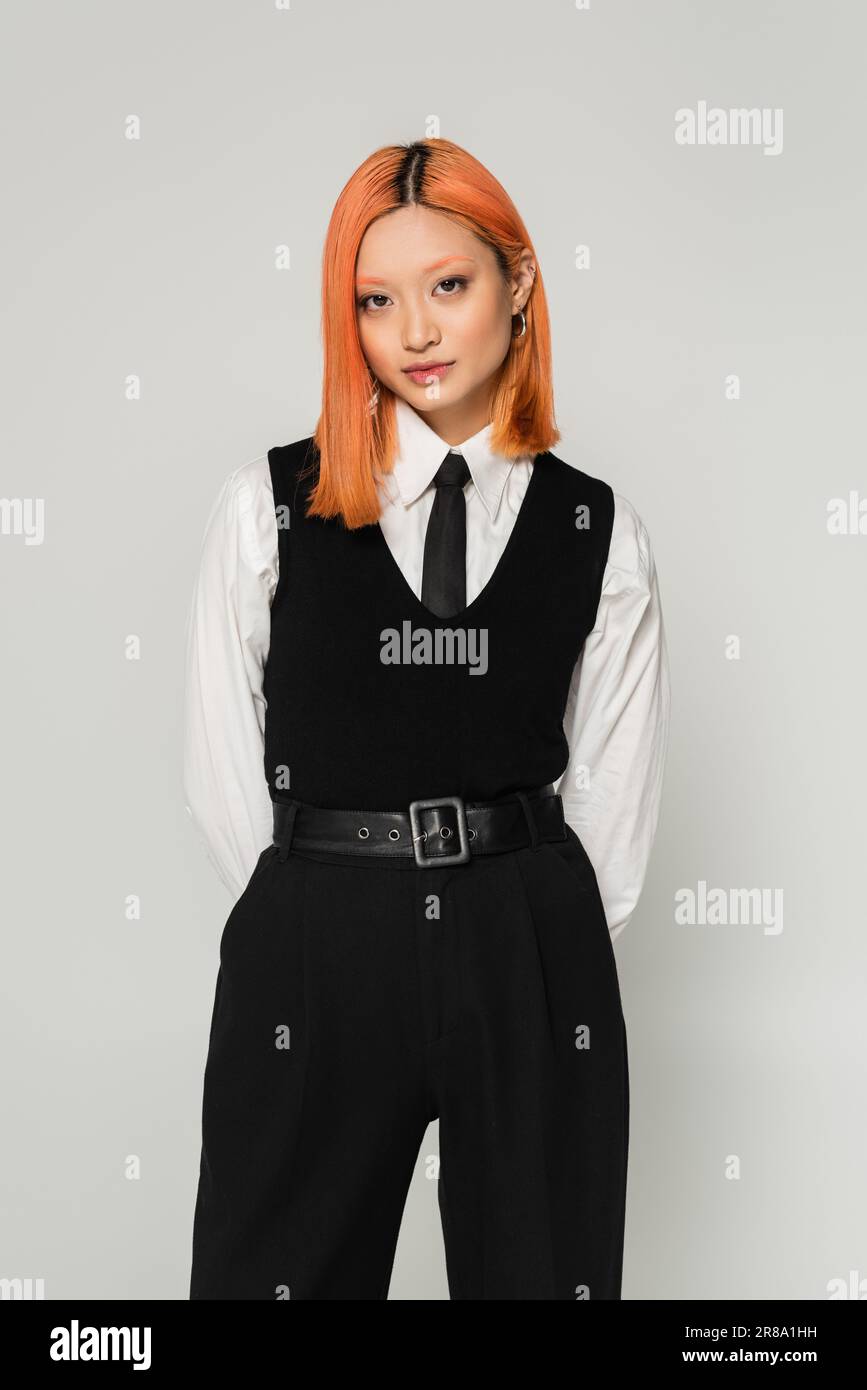 modern and pretty asian woman with colored red hair standing with hands ...