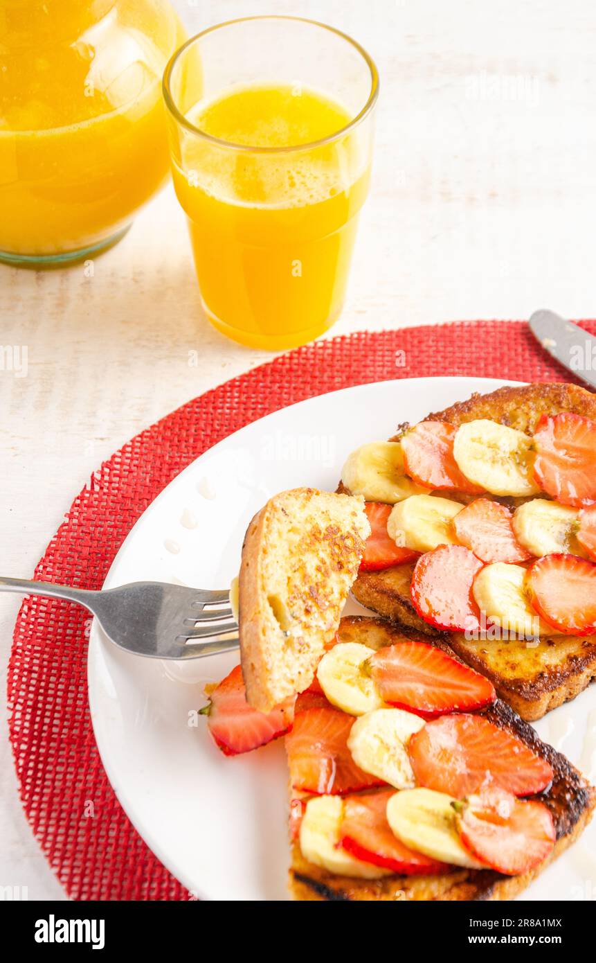 French toast with strawberries, banana and honey. Orange juice. White ...