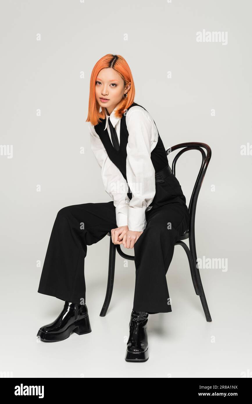 Fashion Shoot Of Alluring And Trendy Asian Woman Looking At Camera While Sitting On Chair On