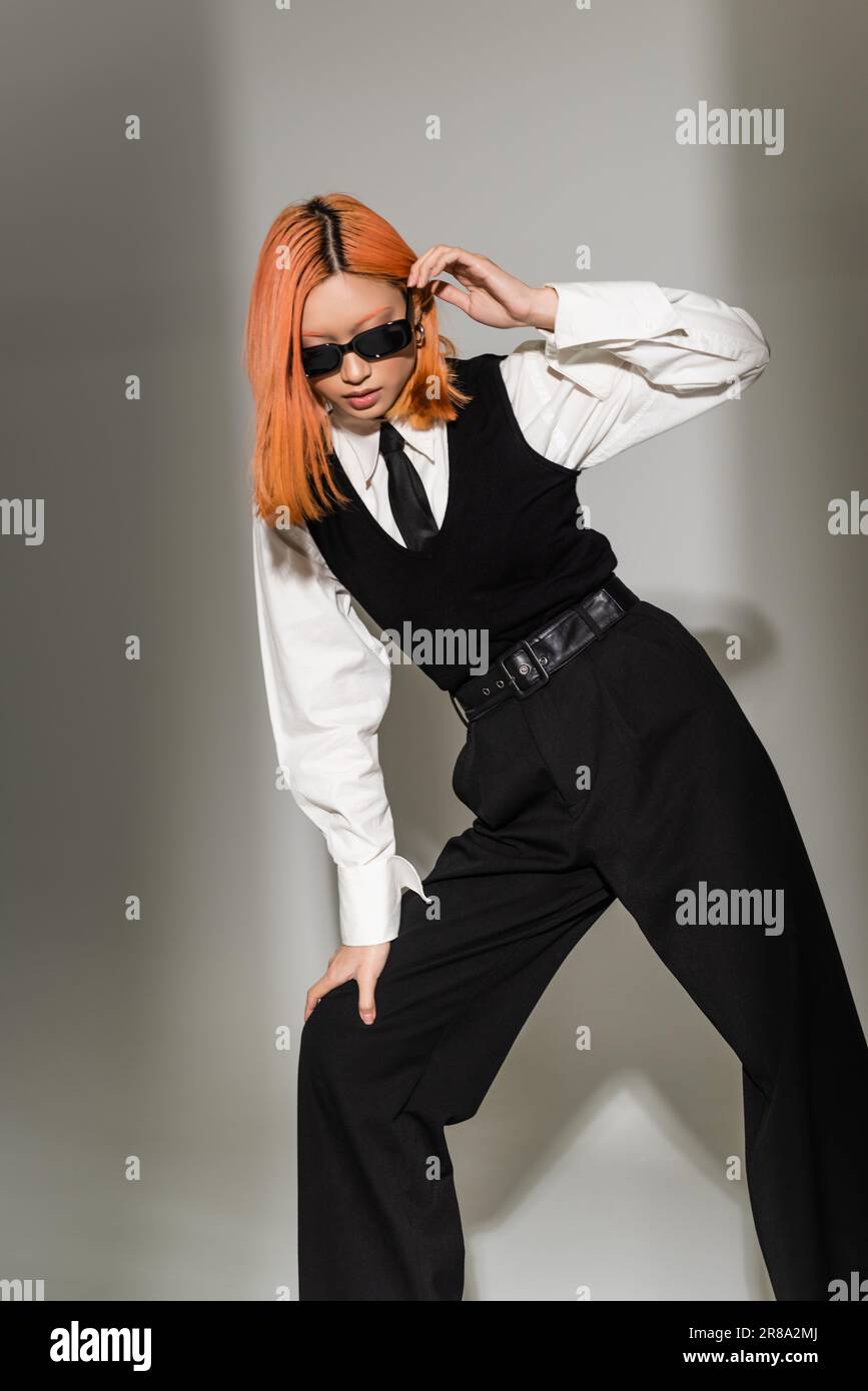 fashion shoot of modern asian woman in dark sunglasses and black and ...