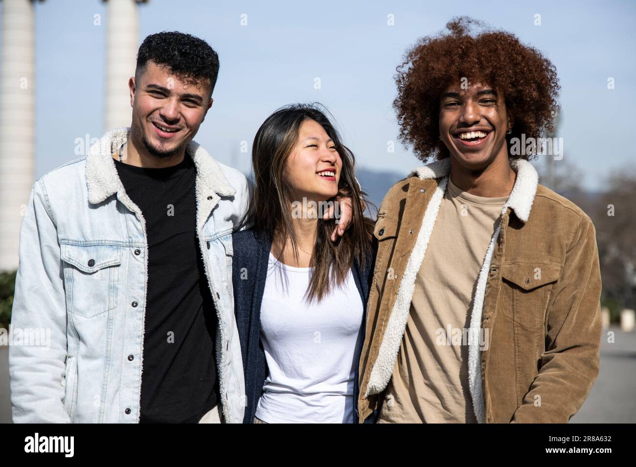 Three happy young people smiling and looking relaxed in the street ...