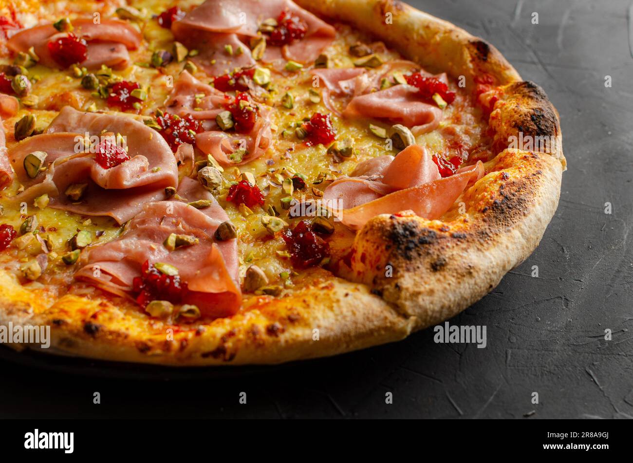 Ham pizza prepared in a wood-fired oven, black background. Closed up ...