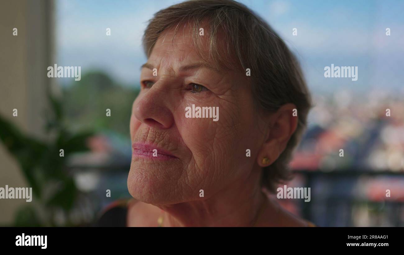 Pensive senior woman close-up face closing and opening eyes with ...