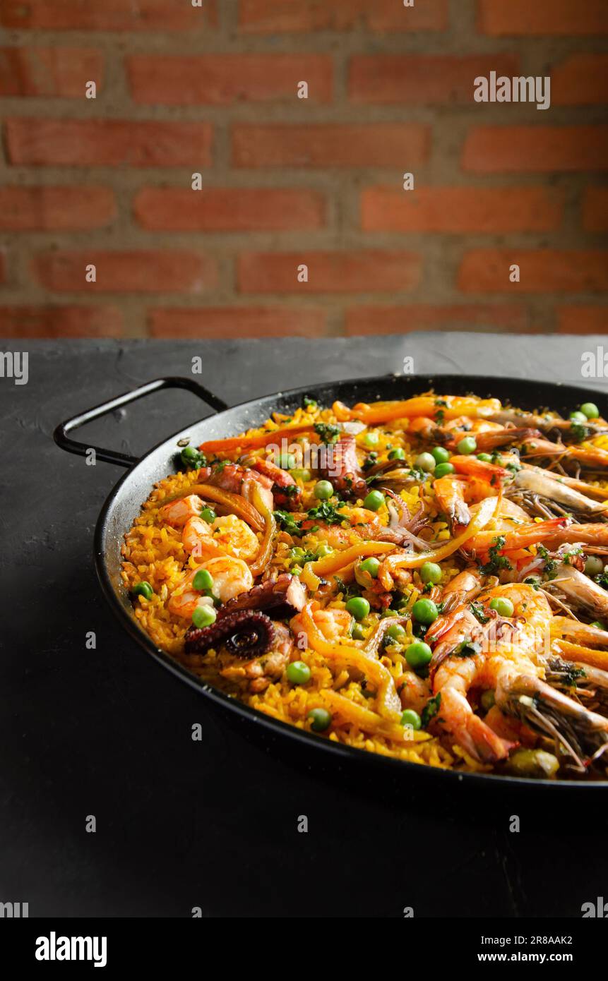 Paella served in paella pan on black background and brick wall Stock ...