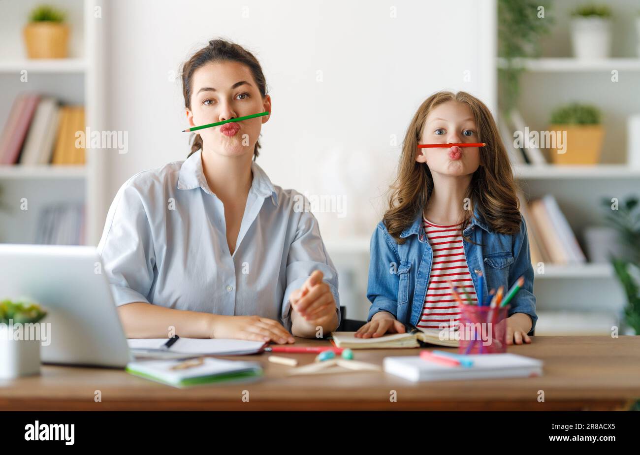 Back to school. Happy child and adult are sitting at desk. Girl doing ...