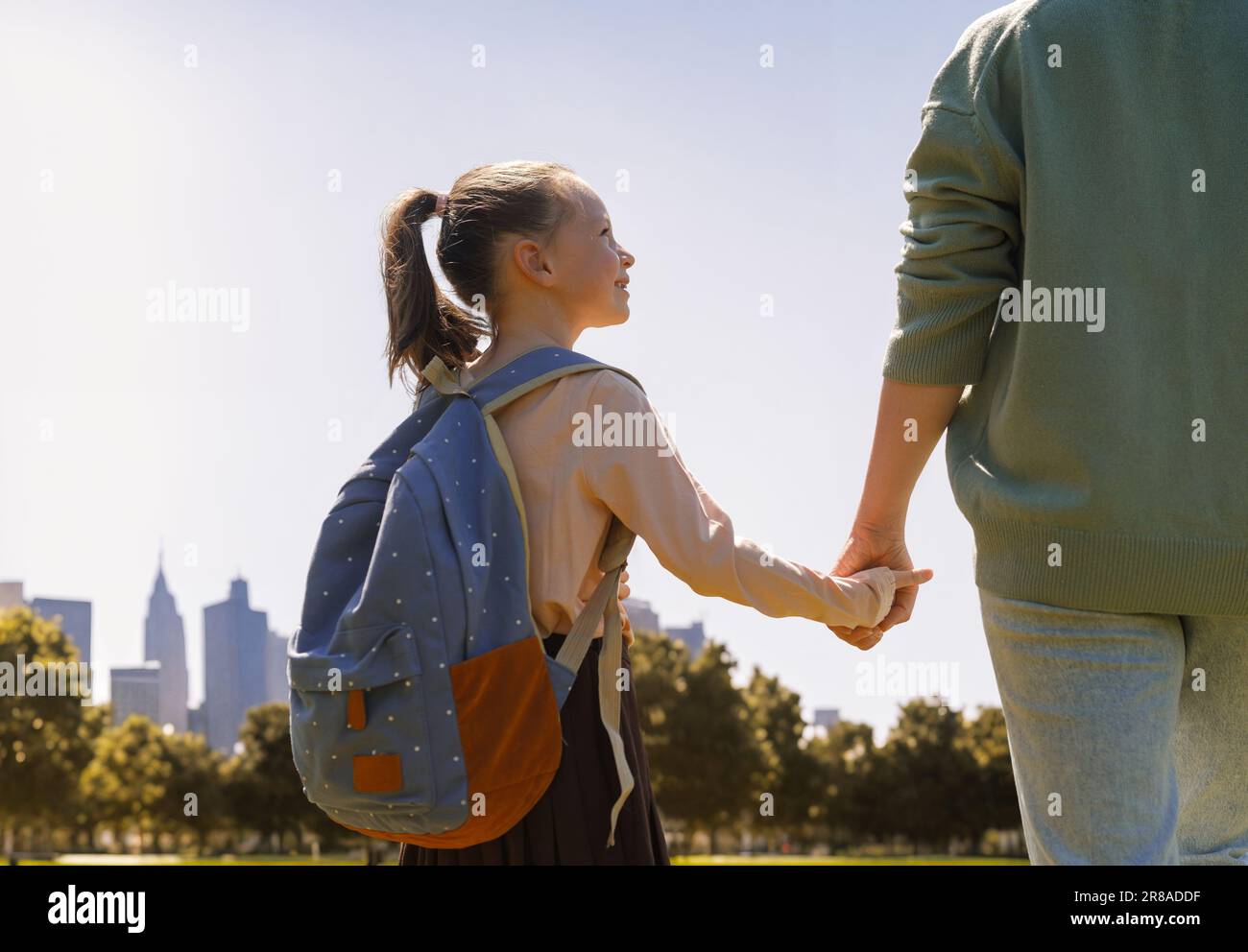Parent and pupil of primary school going hand in hand. Woman and girl ...