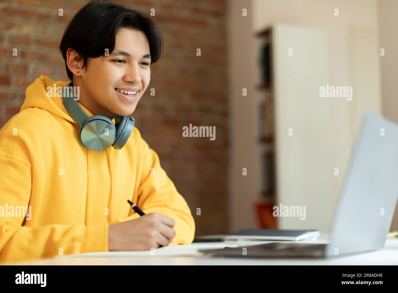Chinese teen guy writing in notebook during webinar at home Stock Photo ...