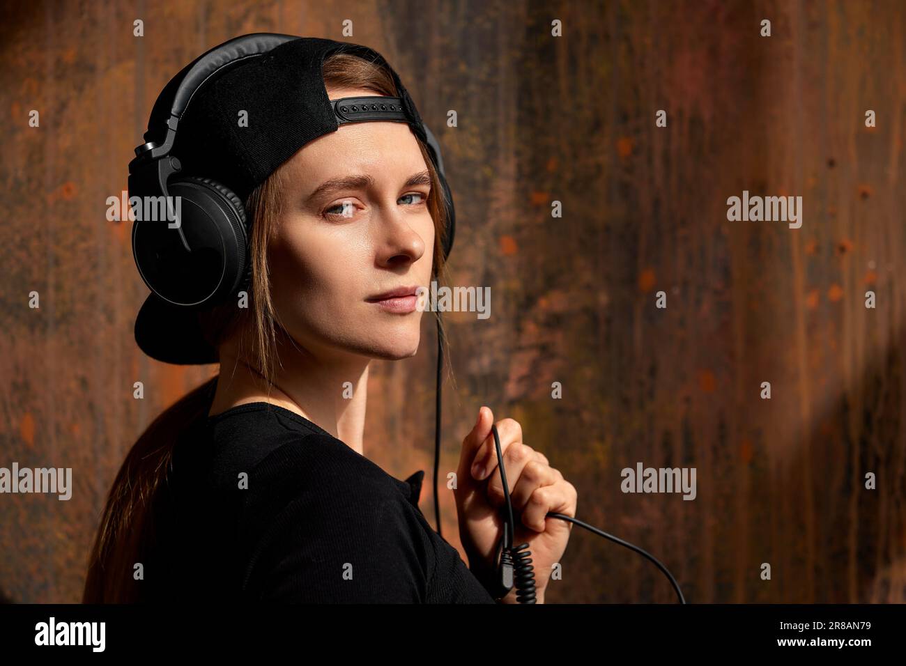 A young long-haired DJ girl in a black top, black baseball cap and ...