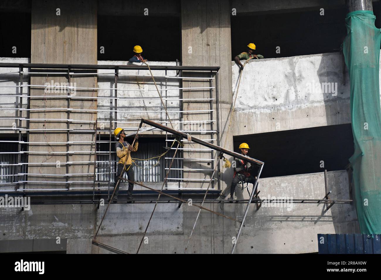 Labourers are seen lifting a iron grill at a construction site in ...