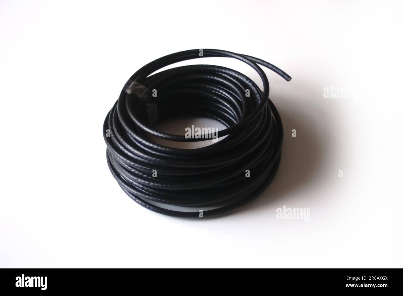 An isolated black rolled electric cable against a white background ...