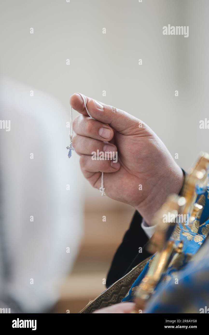 A closeup of a human hand clasping a cross-shaped necklace in a ...